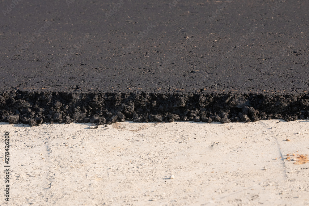 freshly laid black bitumen asphalt with a high edge to the gravel ...