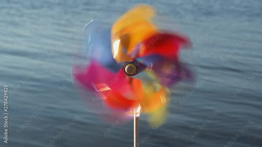 A rotate colored plastic pinwheel with a blowing wind stands on the ...