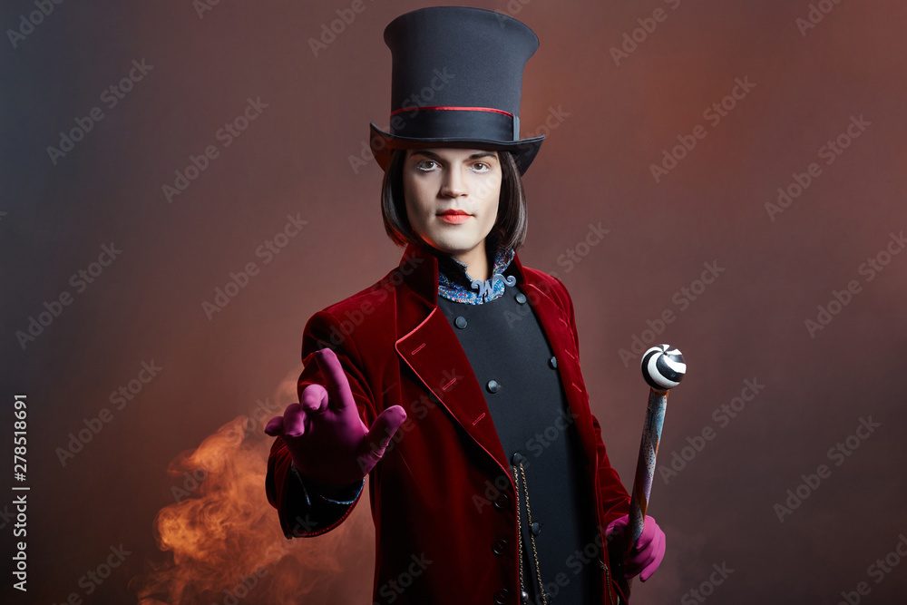 Fabulous circus man in a hat and a red suit posing in the smoke on a ...