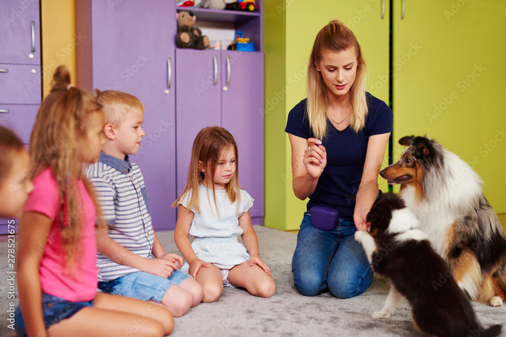 Small group of children playing with therapy dog in the preschool Stock ...