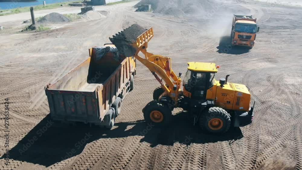 Construction site with rubble getting relocated by vehicles. Mining ...