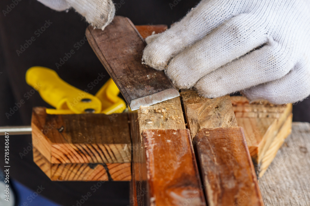 The hand of the carpenter taking the chisel to sharpen the wood plank ...