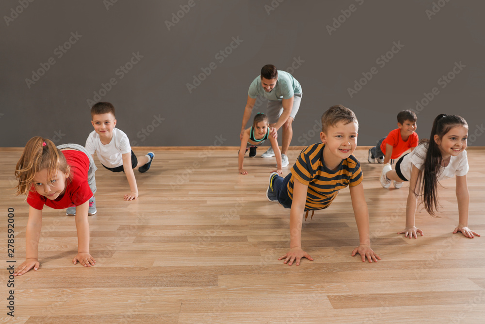 Cute little children and trainer doing physical exercise in school gym ...