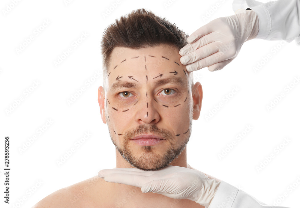 Doctor examining man's face before plastic surgery operation on white ...