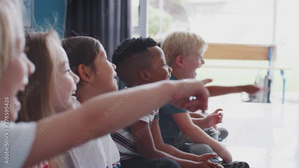 Group Of Laughing Elementary School Pupils Sitting On Floor Listening ...