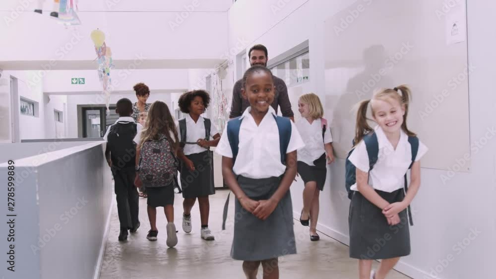 Teacher And Pupils Walking Along Corridor In Busy Elementary School ...