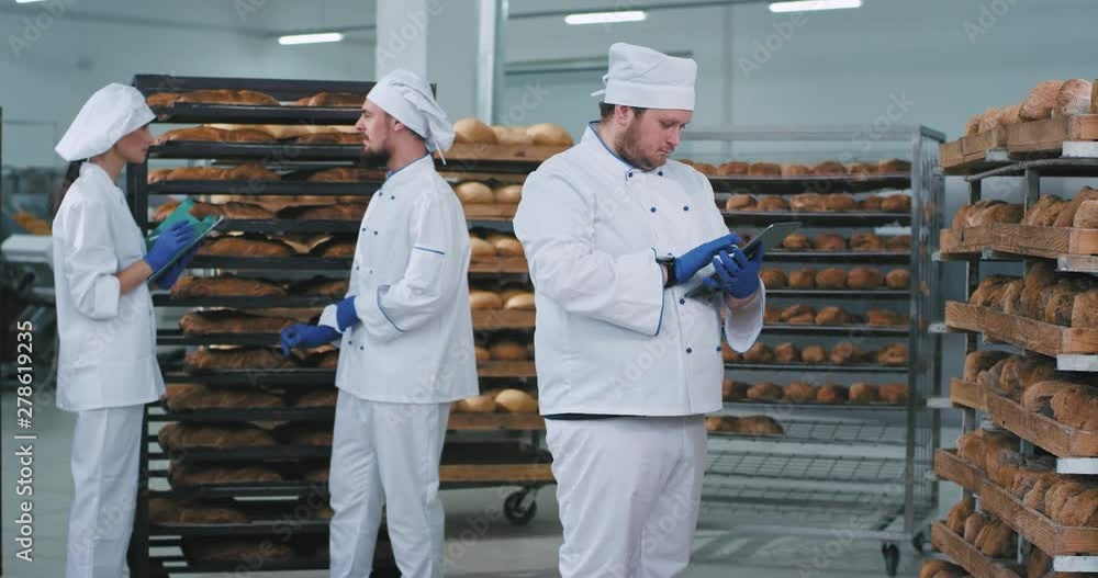 Group of three bakers in a bakery section in a middle of work day they ...