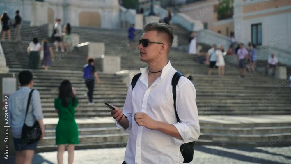 Confident young tourist checking his location on smartphone using ...