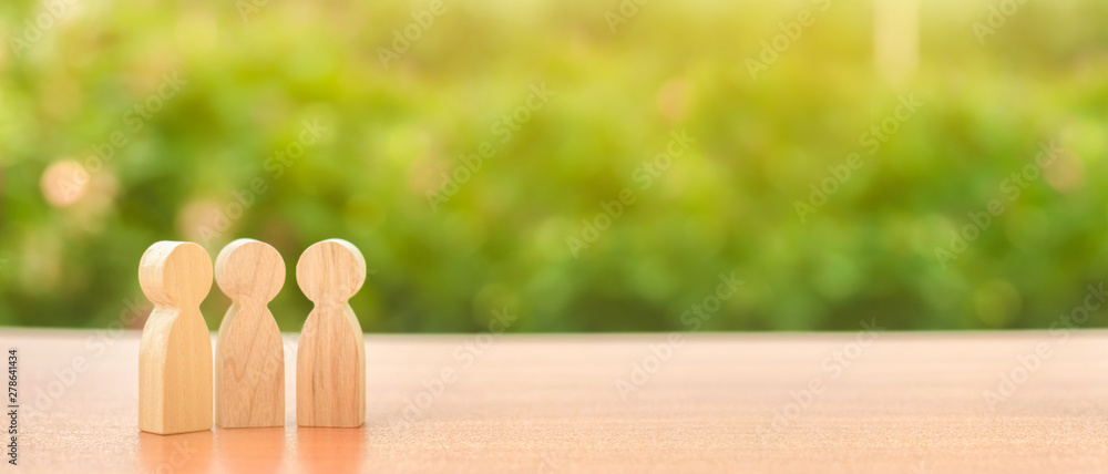 three wooden figures of people stand on the background of nature ...