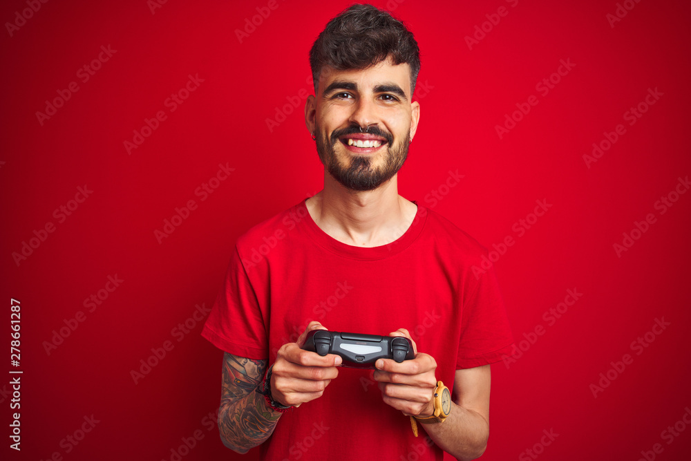 Young gamer man with tattoo playing video game standing over isolated ...