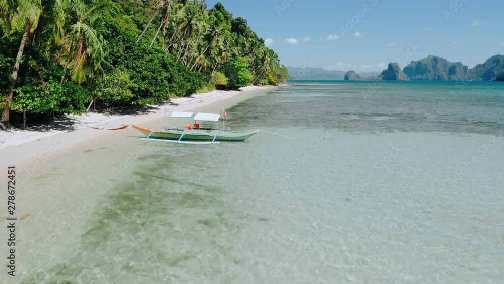 4k Aerial drone flying along exotic cost over banca boat in shallow ...