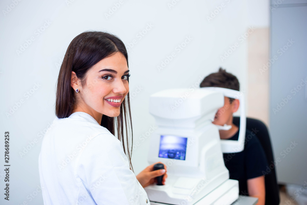 Female oculist using machine for checking eye sight in clinic. Little ...