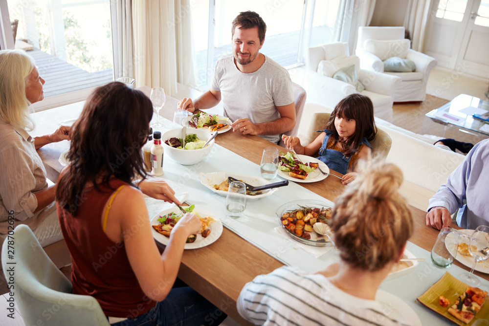 Three generation white family sitting at the dinner table for a family ...
