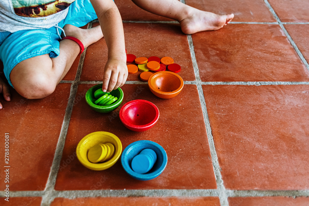 Child playing with a set of colored bowls to fill them with pieces of ...
