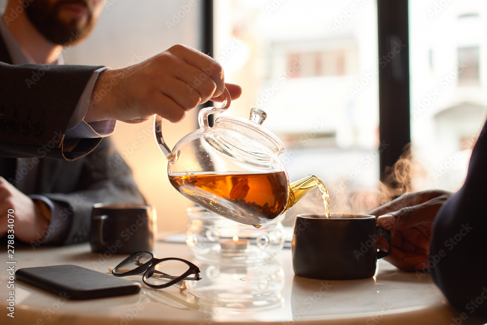 Close up. Man in a suit pouring tea into a cup in coffee shop. Stock ...