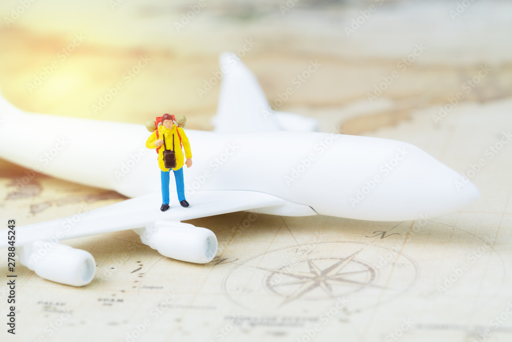 Miniature figure adventure backpacker standing on small airplane on ...