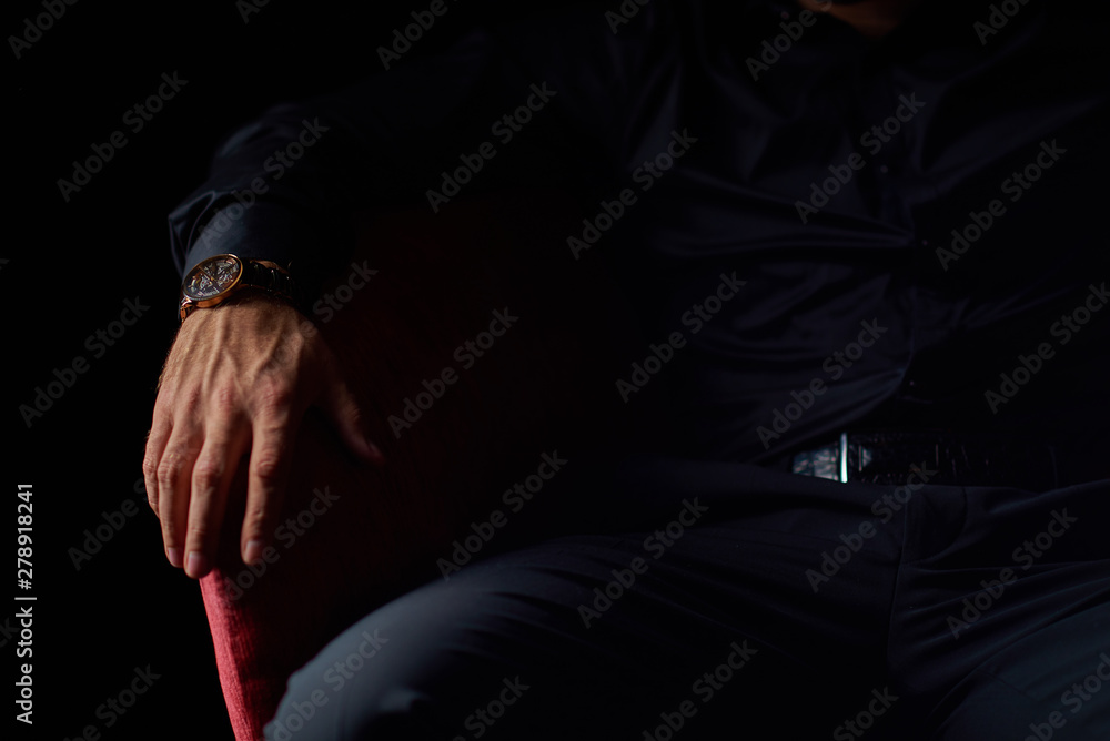 male businessman in a black suit sitting in red chair, black background ...