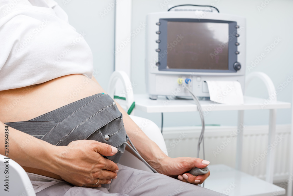 Pregnant woman performing cardiotocography or CTG monitoring fetal ...
