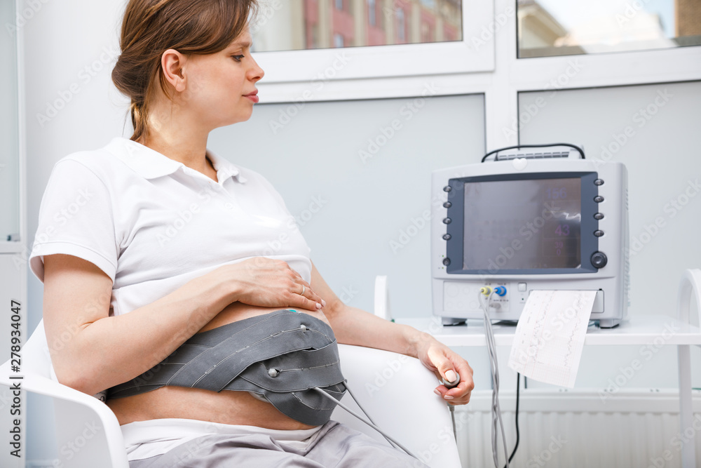 Pregnant woman performing cardiotocography or CTG monitoring fetal ...