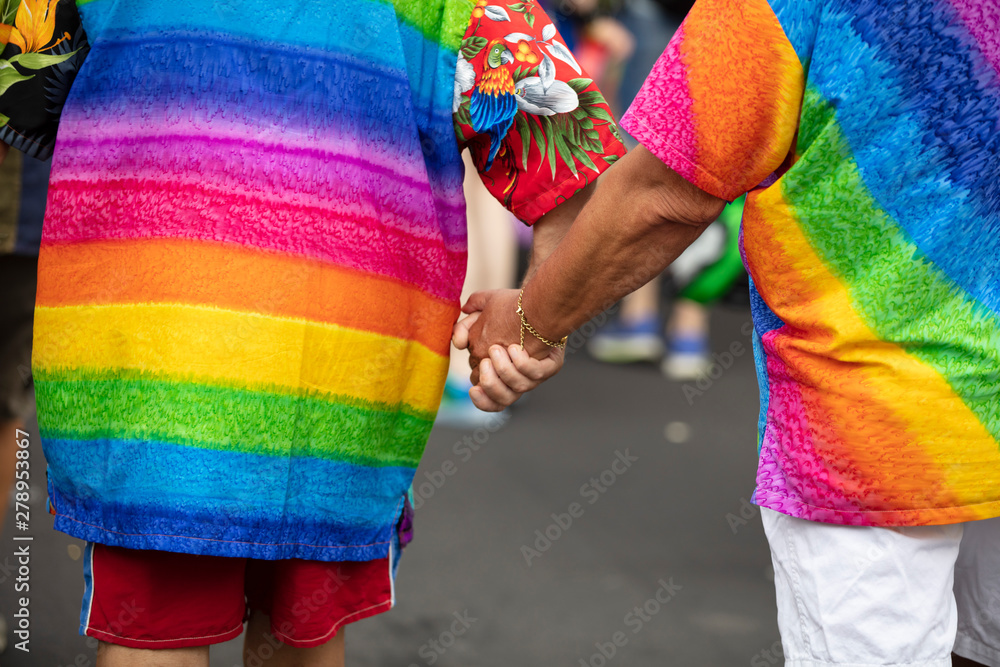 Foto de Two gay men wrapped in gay pride flags holding hands with each ...