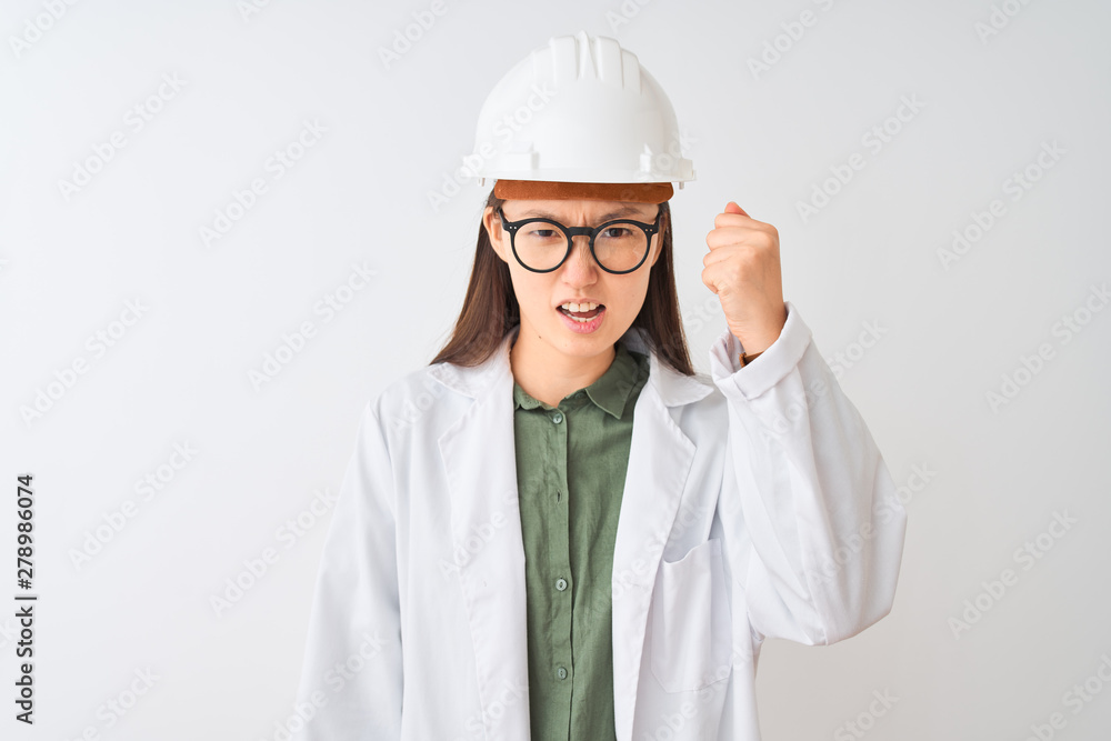 Young chinese engineer woman wearing coat helmet glasses over isolated white background angry ...
