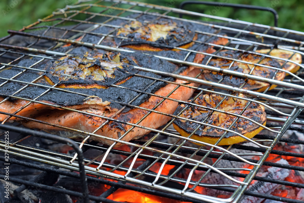 Grilling salmon with lemon slices. Skin of a fish has burned to black ...