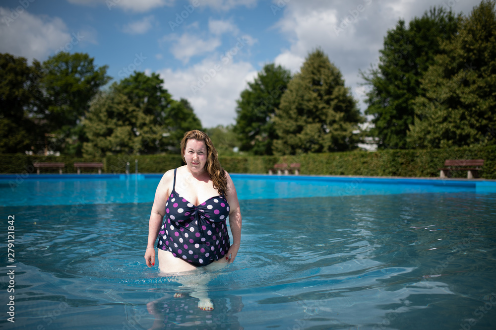 confident large plus size model standing in swimming pool in front of ...