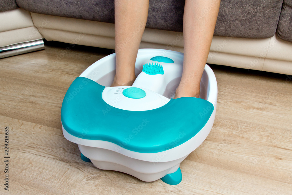 Feet in a vibrating foot massager. Electric massage bath. Foot bath ...