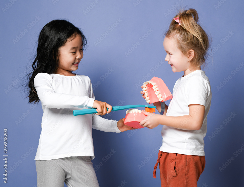 Two children friends with toothbrushes hold big dental implant model ...