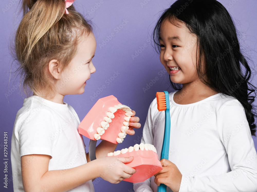 Two children friends with toothbrushes hold big dental implant model ...