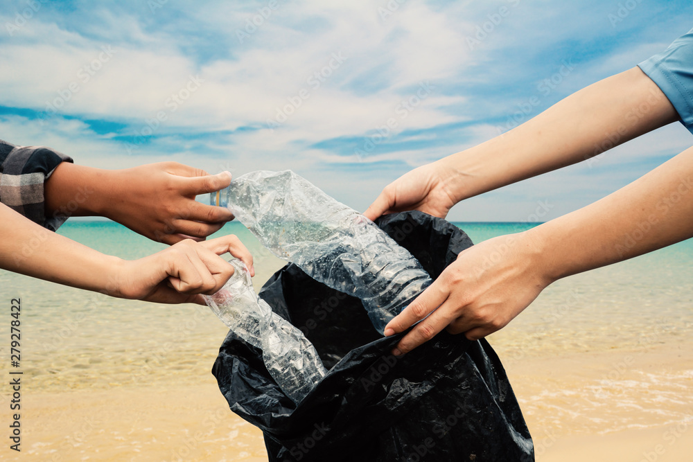 The volunteer picking up a bottle plastic in to a bin bag and the sea ...