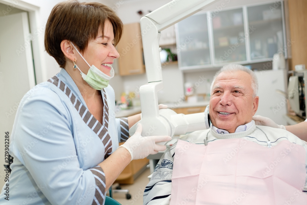 Foto de Female dentist with x-ray machine scanning senior man 65-70 ...