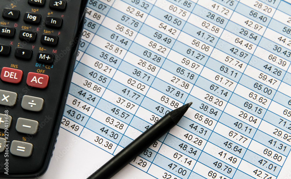 Scientific calculator and black pencil over financial spreadsheet table ...
