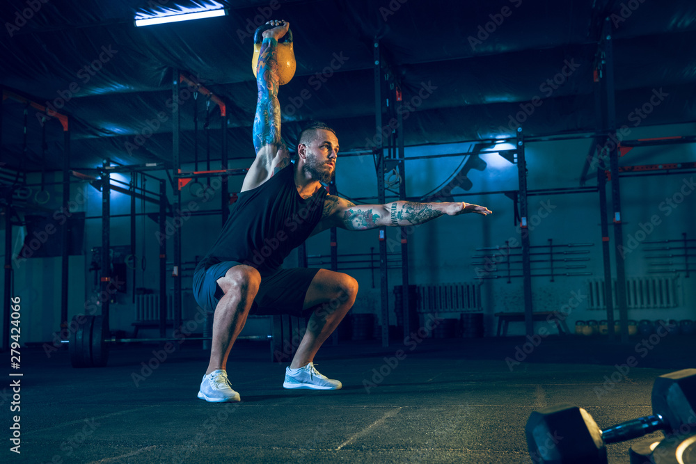 Young healthy man athlete doing exercise with the weights in the gym ...
