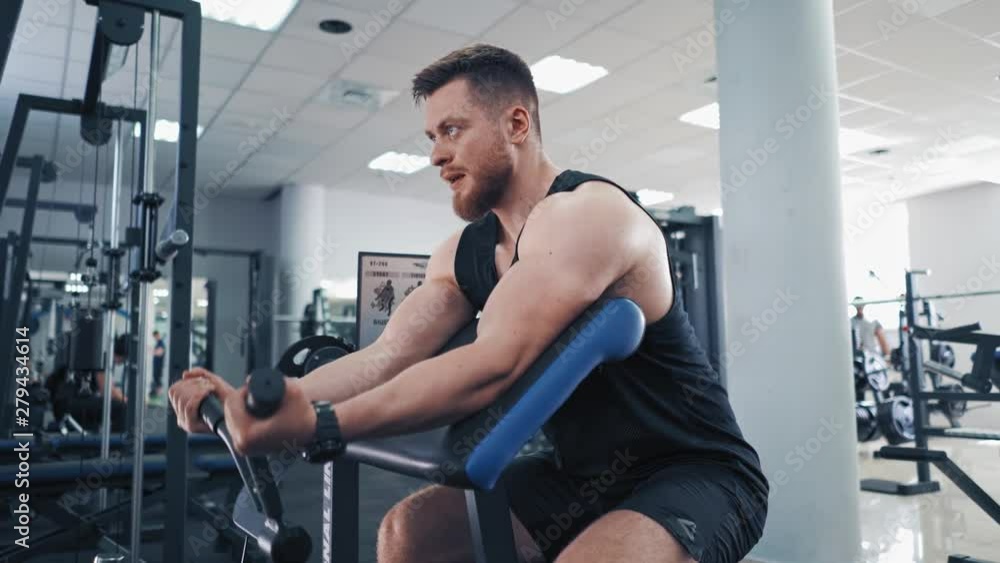 Side view of an athletic man during workout in a gym. Bodybuilder ...