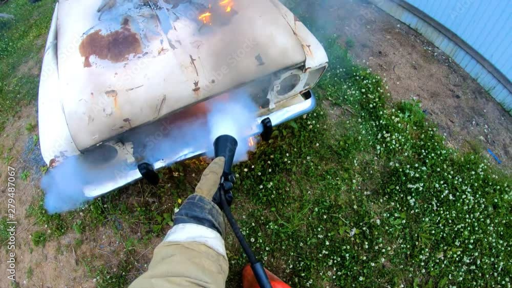 Extinguishing a burning car with a fire extinguisher.Firefighter ...