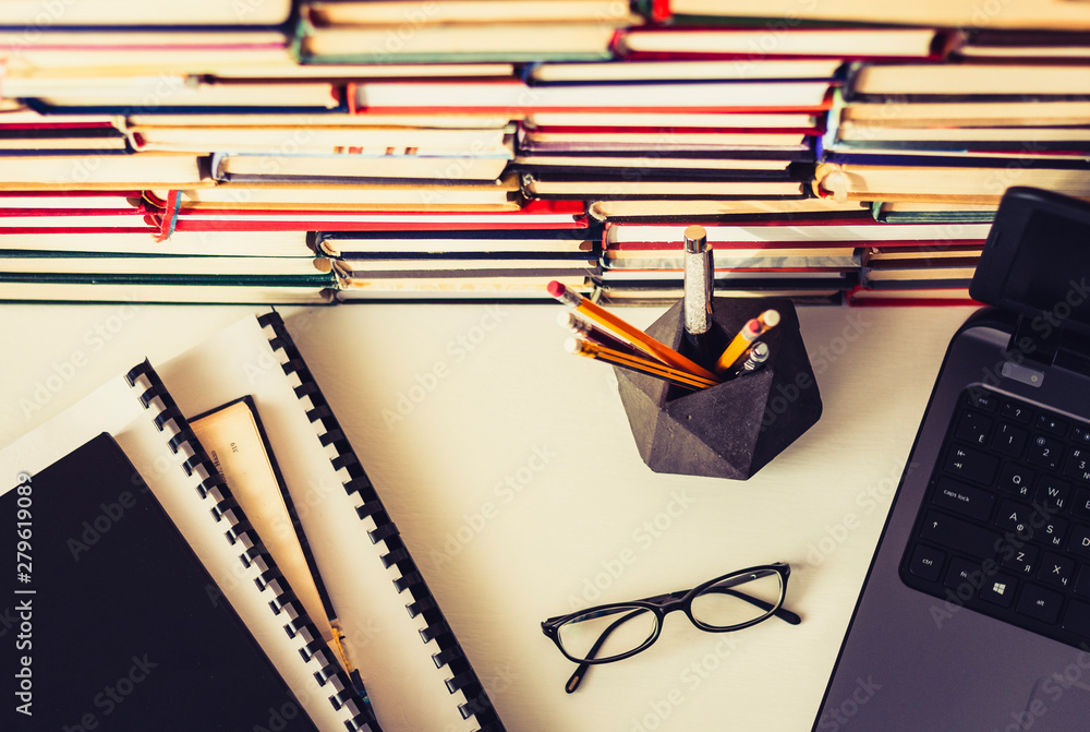 Stack of books, notebook, laptop, glasses in office background for ...