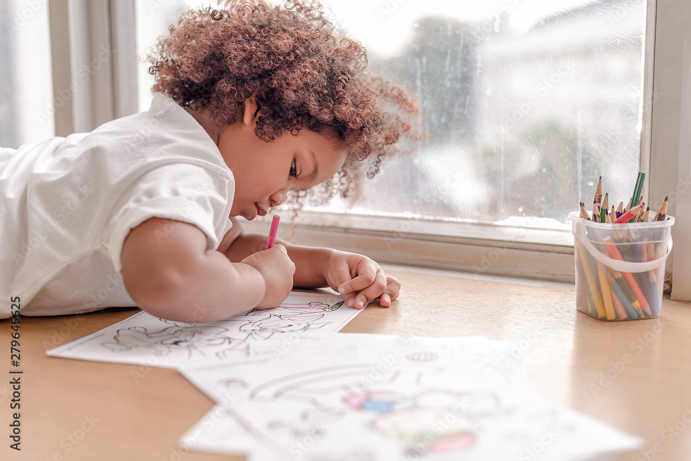 Little toddler girl laying down concentrate on drawing. Mix African ...