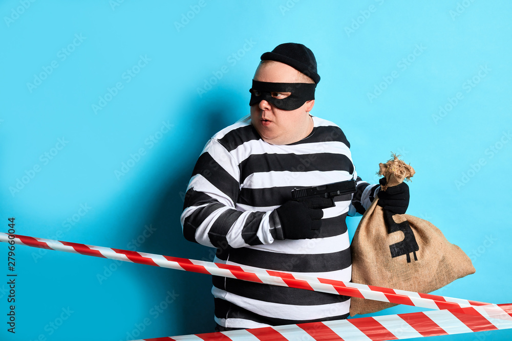 careful plump prisoner wearing mask looking back, isolated blue ...