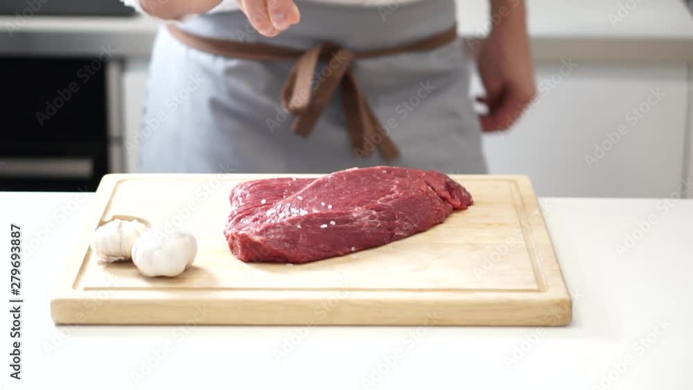 Chef salted with coarse salt beef meat on a cutting Board. Close-up of ...