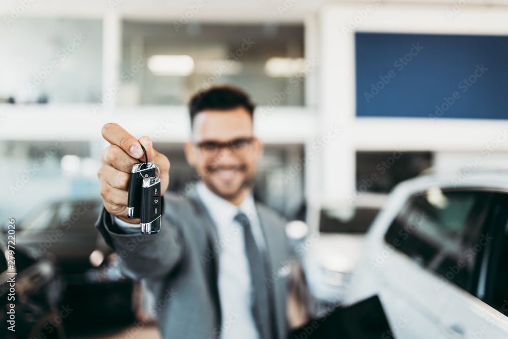 Good looking, cheerful and friendly salesman holding keys and posing in ...