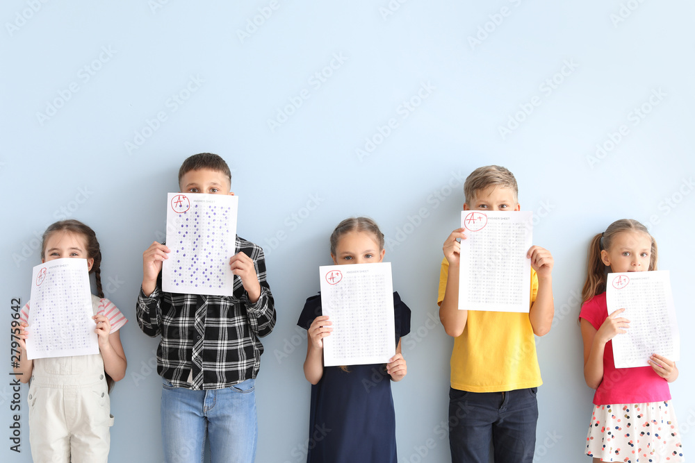 Children with answer sheets for school test on light color background ...
