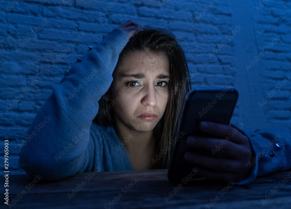 Young sad woman alone looking at smart phone in fear suffering Internet ...