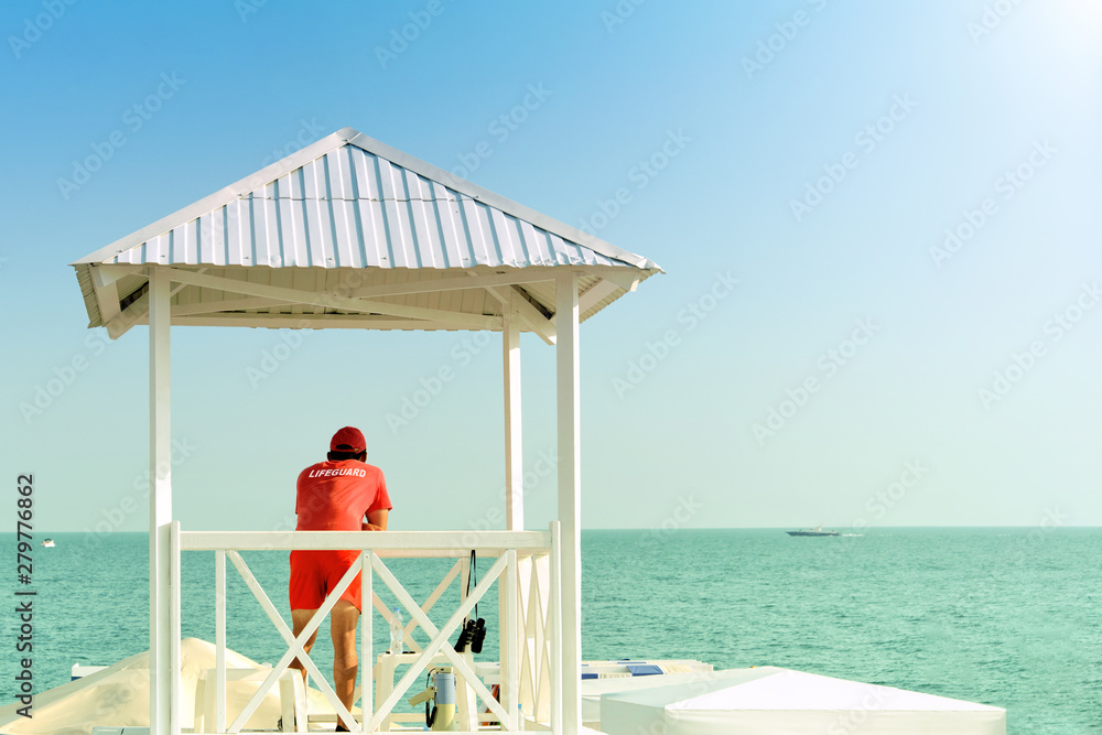 lifeguard on sea beach in watch tower on rescue duty against blue ocean ...