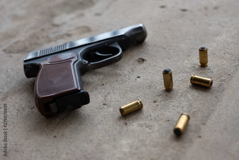 traumatic metal gun with 9 mm bullets on a gray concrete background ...