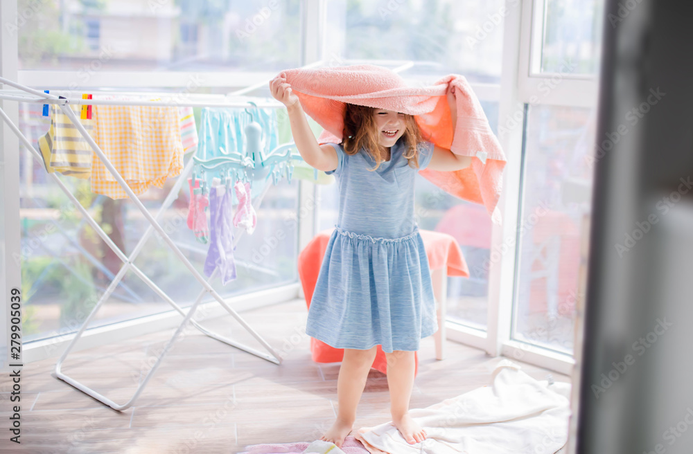 Child in laundry room. Clean washed clothes on drying rack. Mother's ...