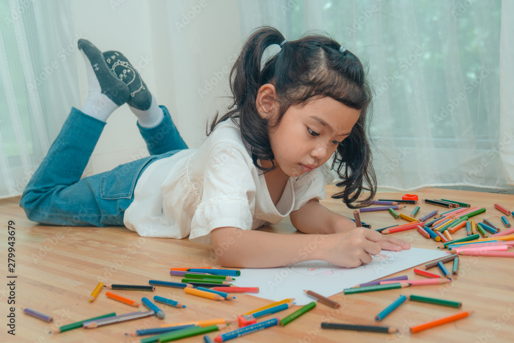 portrait of child girl laying on floor drawing picture with color ...