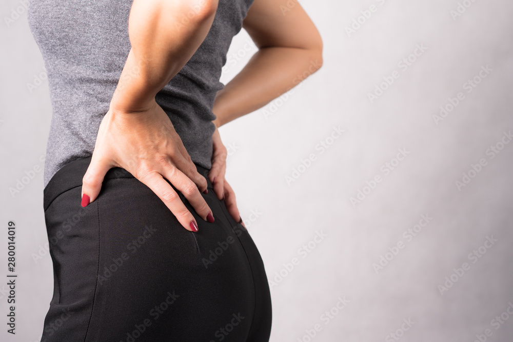 Closeup of woman's hands touching her lower back to reduce the pain ...