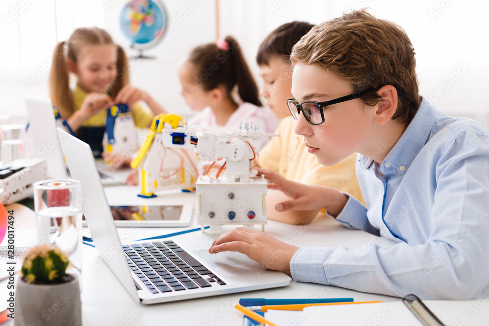 Boy using laptop, assembling robot in class Stock Photo | Adobe Stock