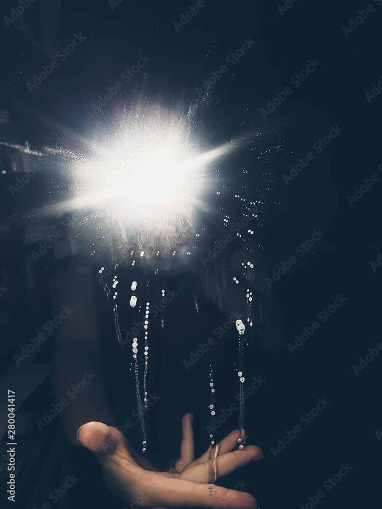 Bright flare of light above the nand. Magical flash on dark background ...